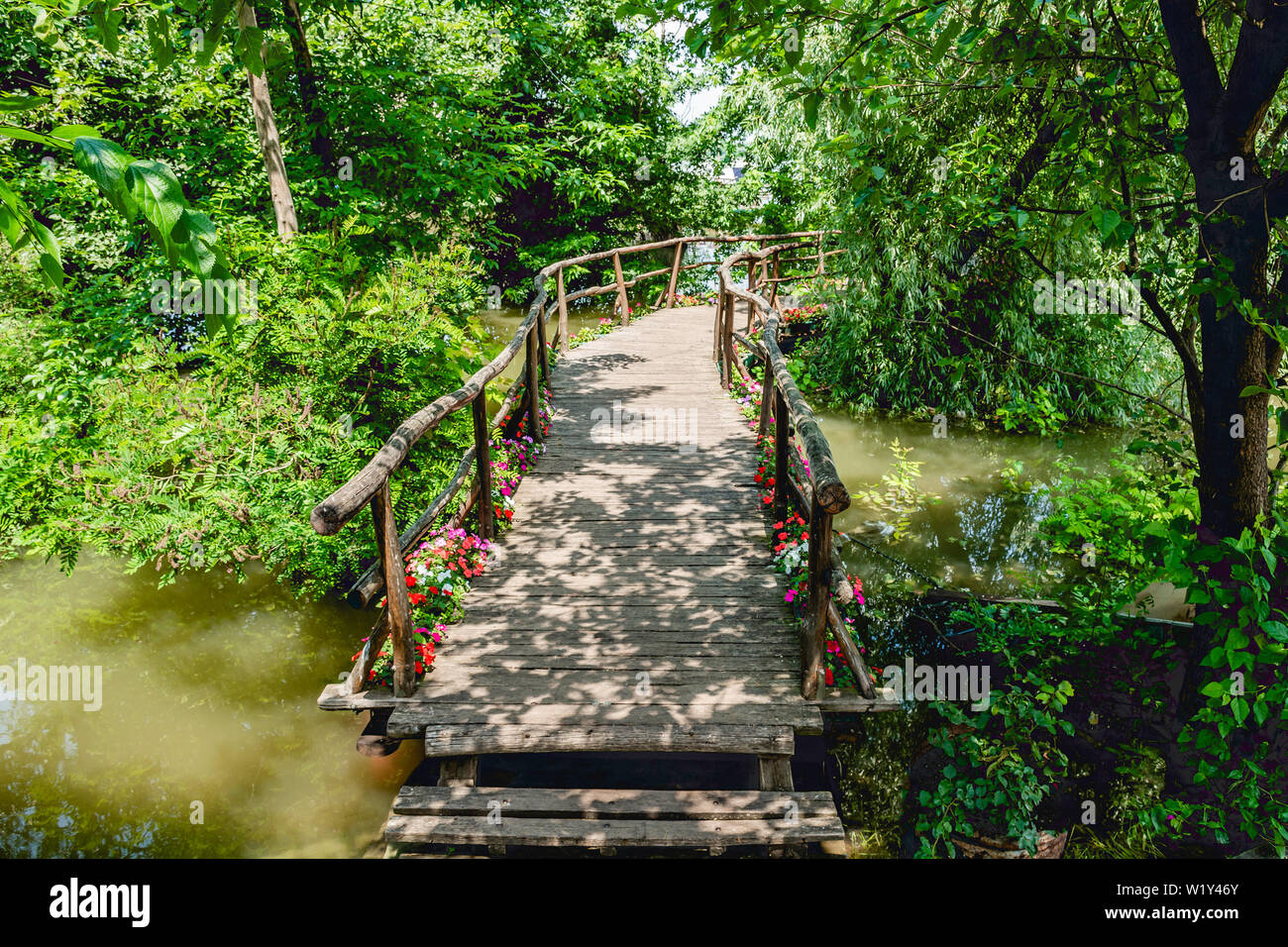 Hand made small romantic wooden bridge over the river water surrounded ...