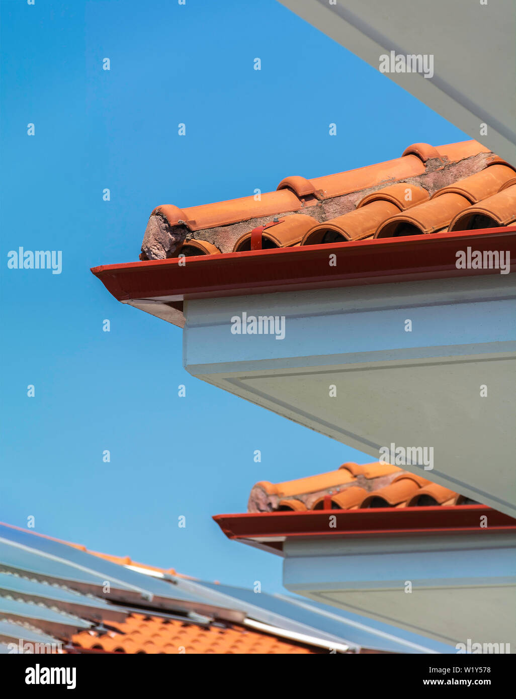 Corners of roof tops against blue clear sky with solar panels vertical ...
