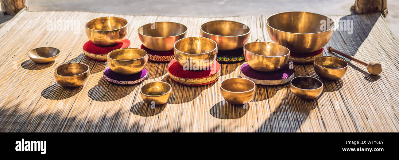 Tibetan singing bowls on a straw mat against a waterfall BANNER, LONG ...