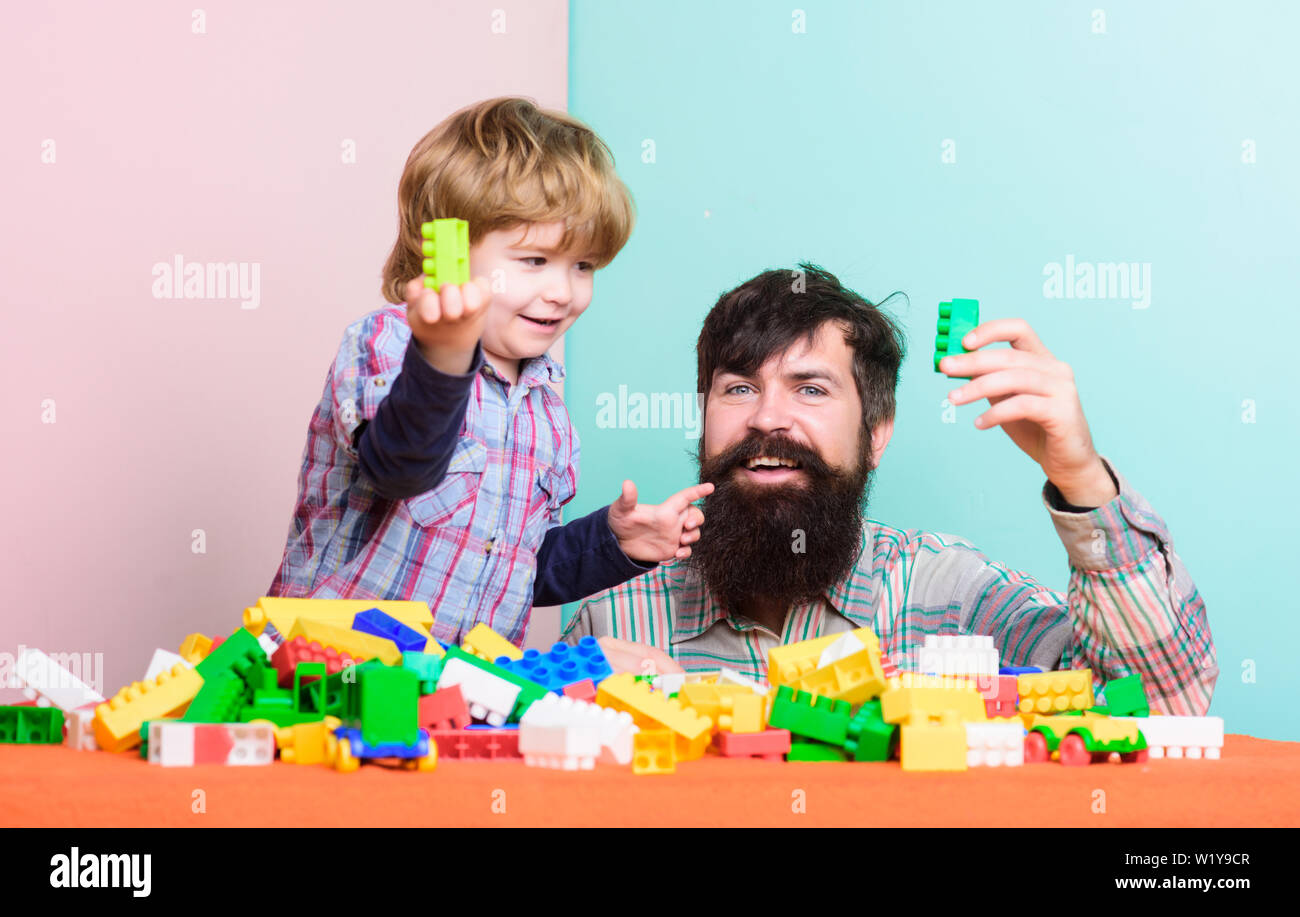 Dad and kid build of plastic blocks. Father and son create colorful ...