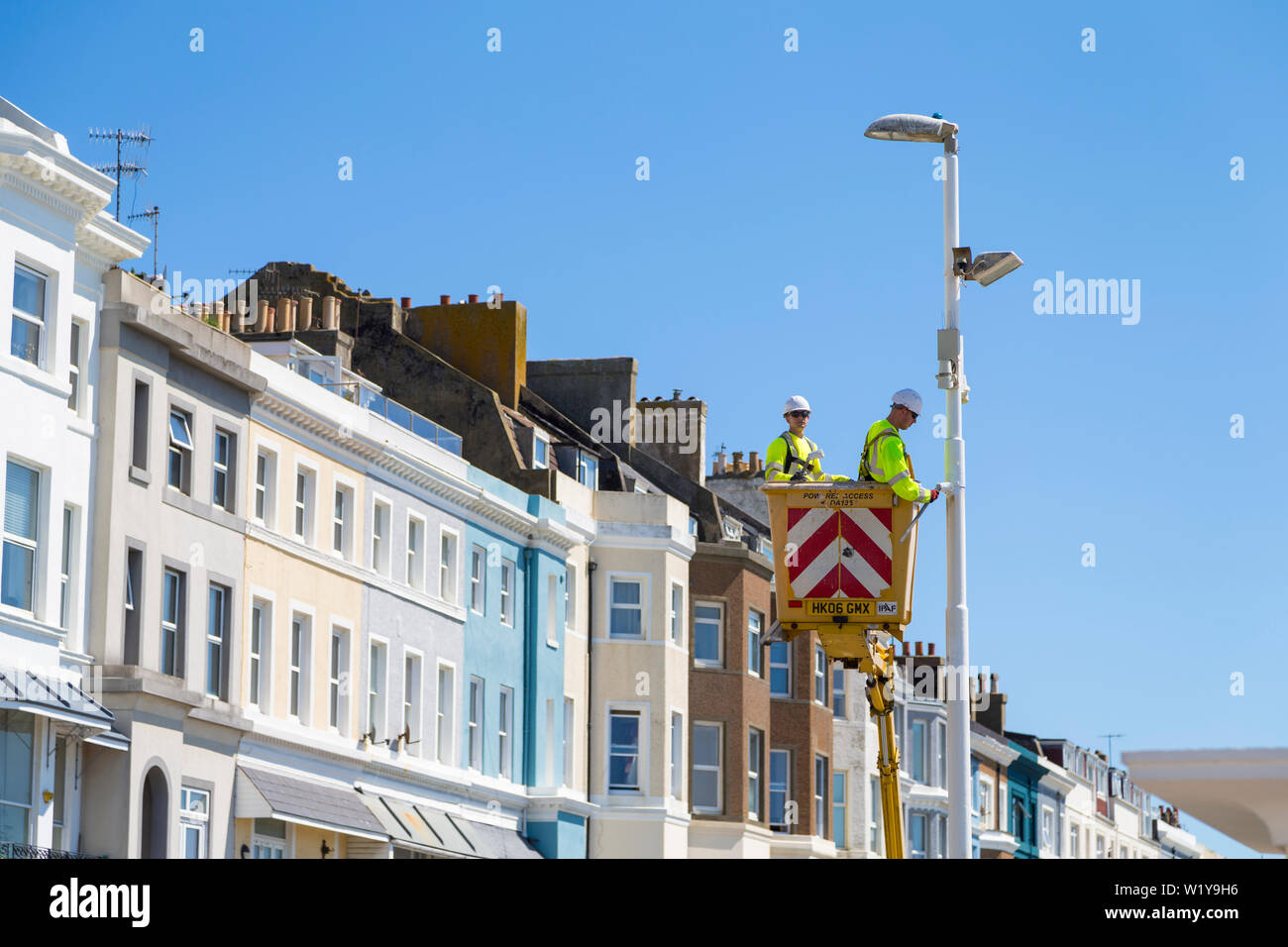 Two men on a cherry picker working at height painting lamp posts ...