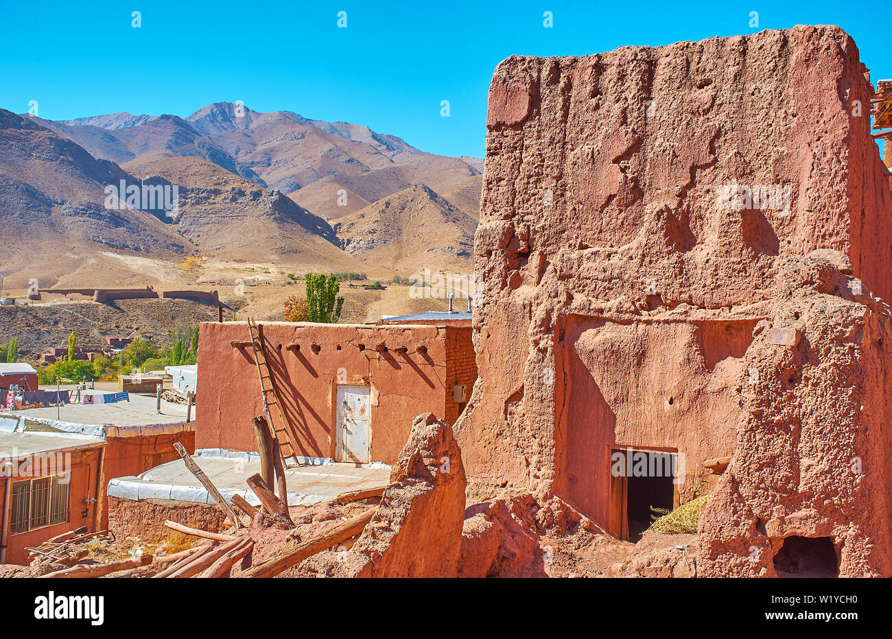 The ruined abandoned red adobe building in terrace Abyaneh village with ...