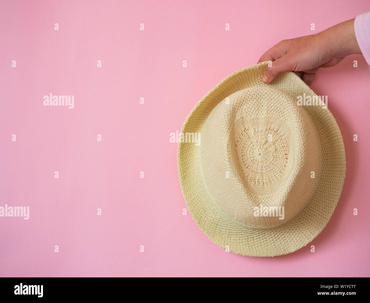 Hand holding hat on pink background with copy space Stock Photo - Alamy