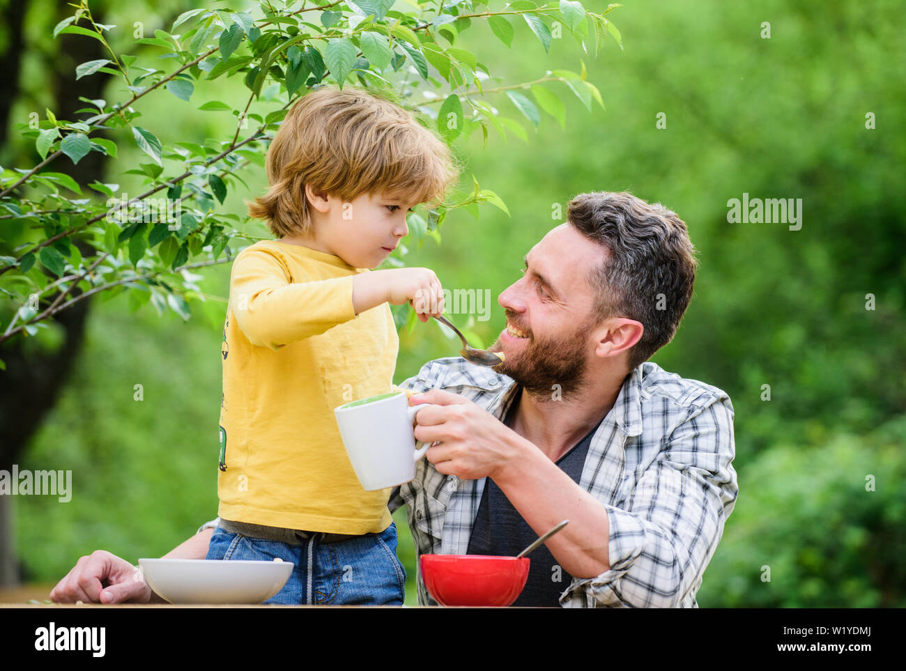 Food habits. Little boy with dad eating food nature background. Summer ...
