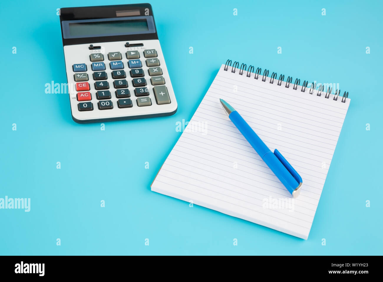 Calculator, blue pen and notepad on blue background Stock Photo - Alamy