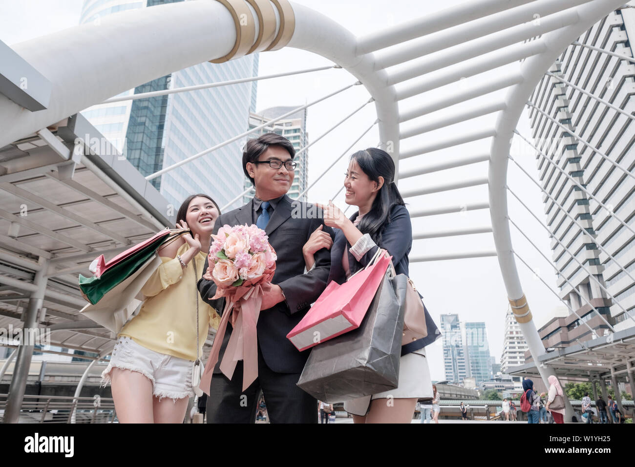 Two asian woman cuddle snuggle with smart businessman holding bouquet ...