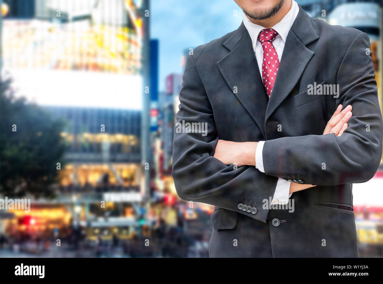Businessman crossed arms on downtown square background Stock Photo - Alamy