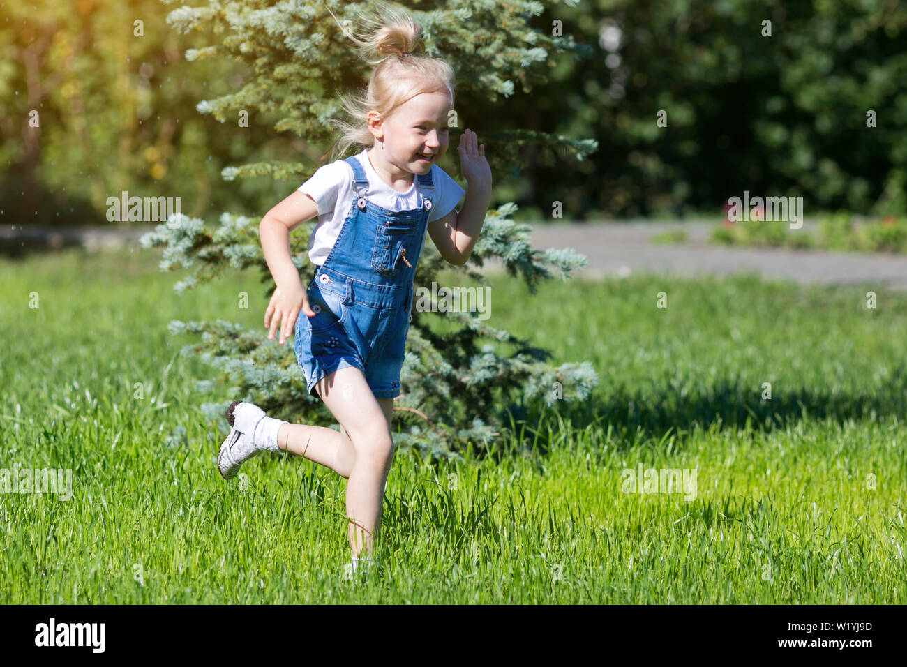 Girls running around the lawn with grass playing with splashes of water ...