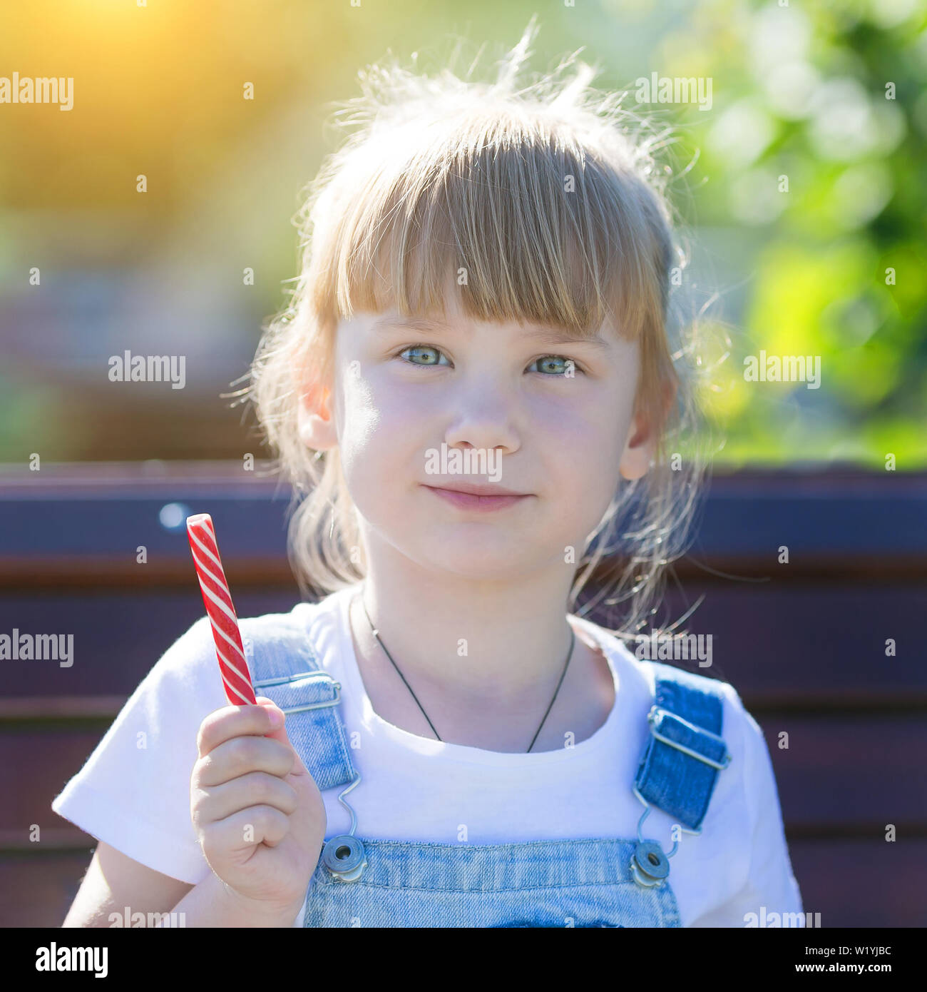 girl of preschool age eats a sweet candy on a sunny summer day Stock ...