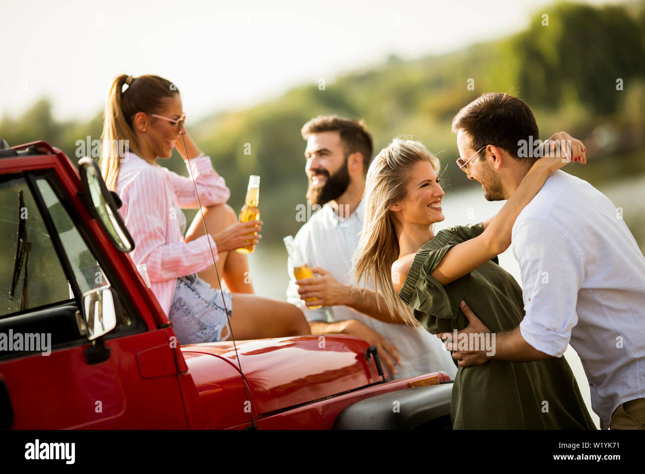 Four young people having fun in convertible car by river Stock Photo ...