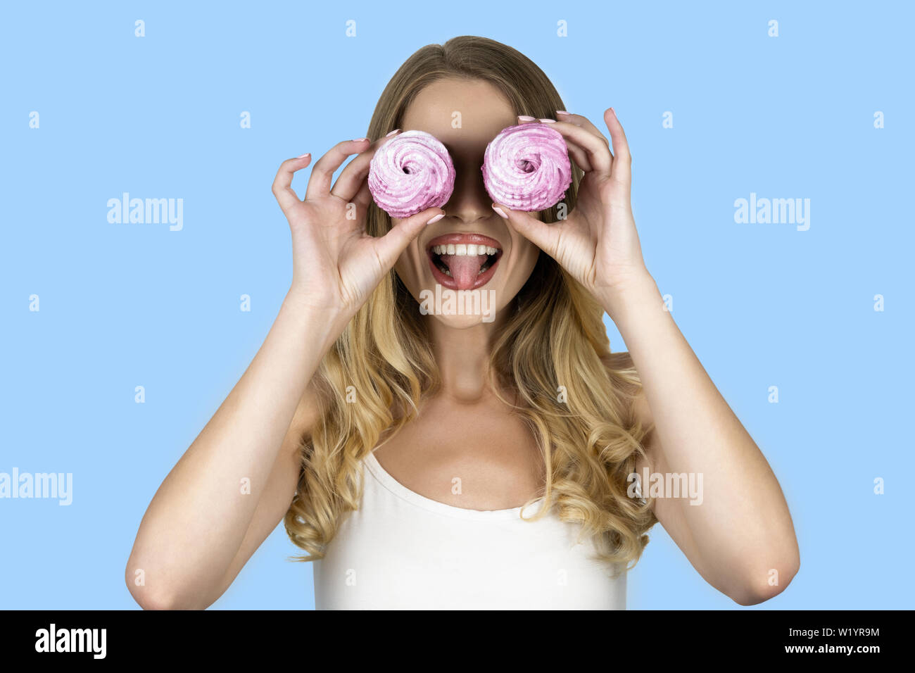 girl holding two cupcakes near her face isolated blue background Stock ...