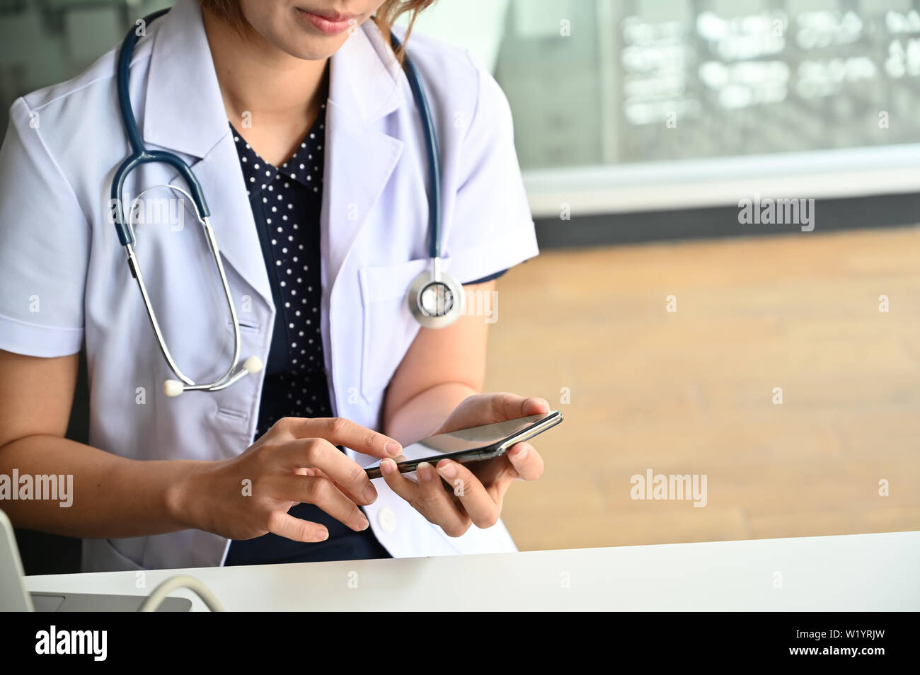 Female doctor using smartphone with cropped shot Stock Photo - Alamy