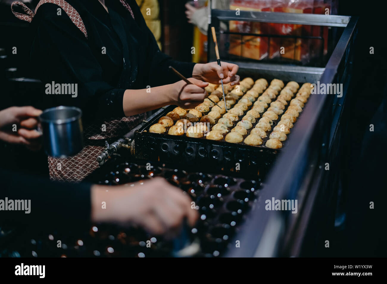 Closeup hand making takoyaki. Takoyaki is a ball Japanese snack popular ...
