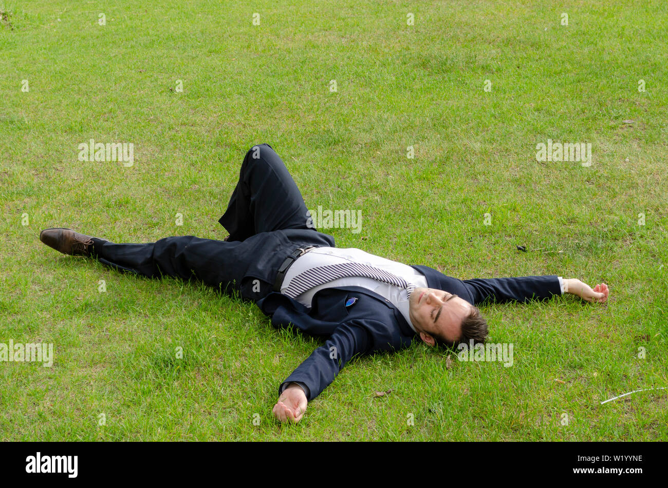 Portrait of handsome businessman relaxing outdoor in the green grass at ...