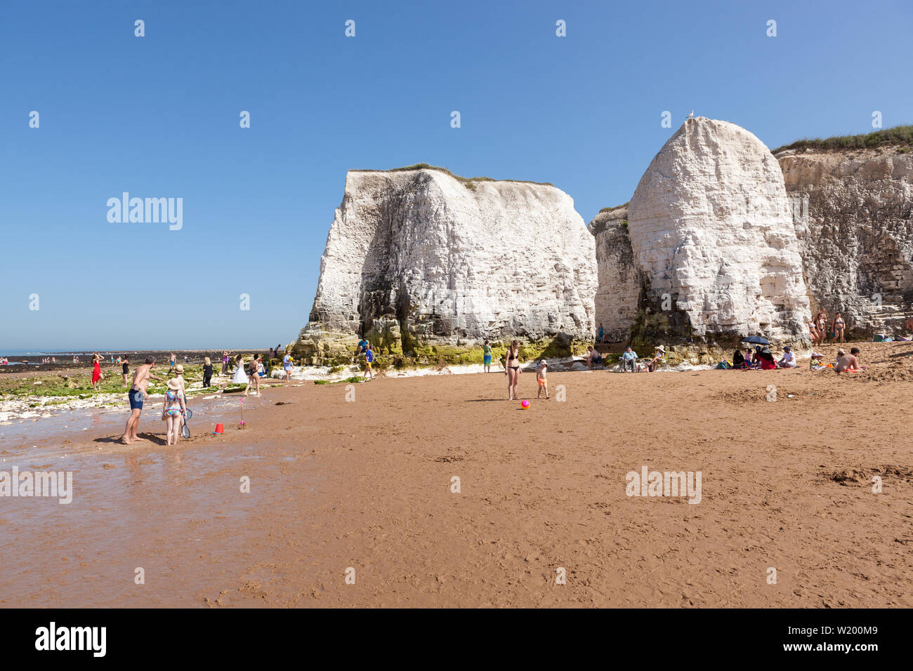 Crowd of people on the sandy beach near the chalk stacks of Botany Bay ...