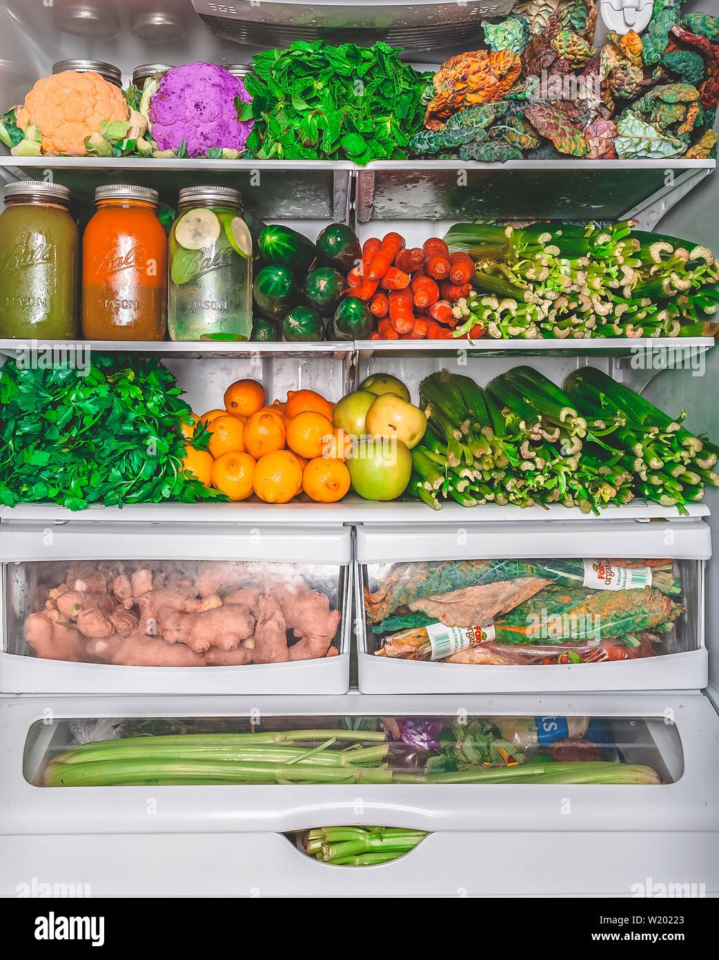 An opened door of a refrigerator with various types of vegetables and ...
