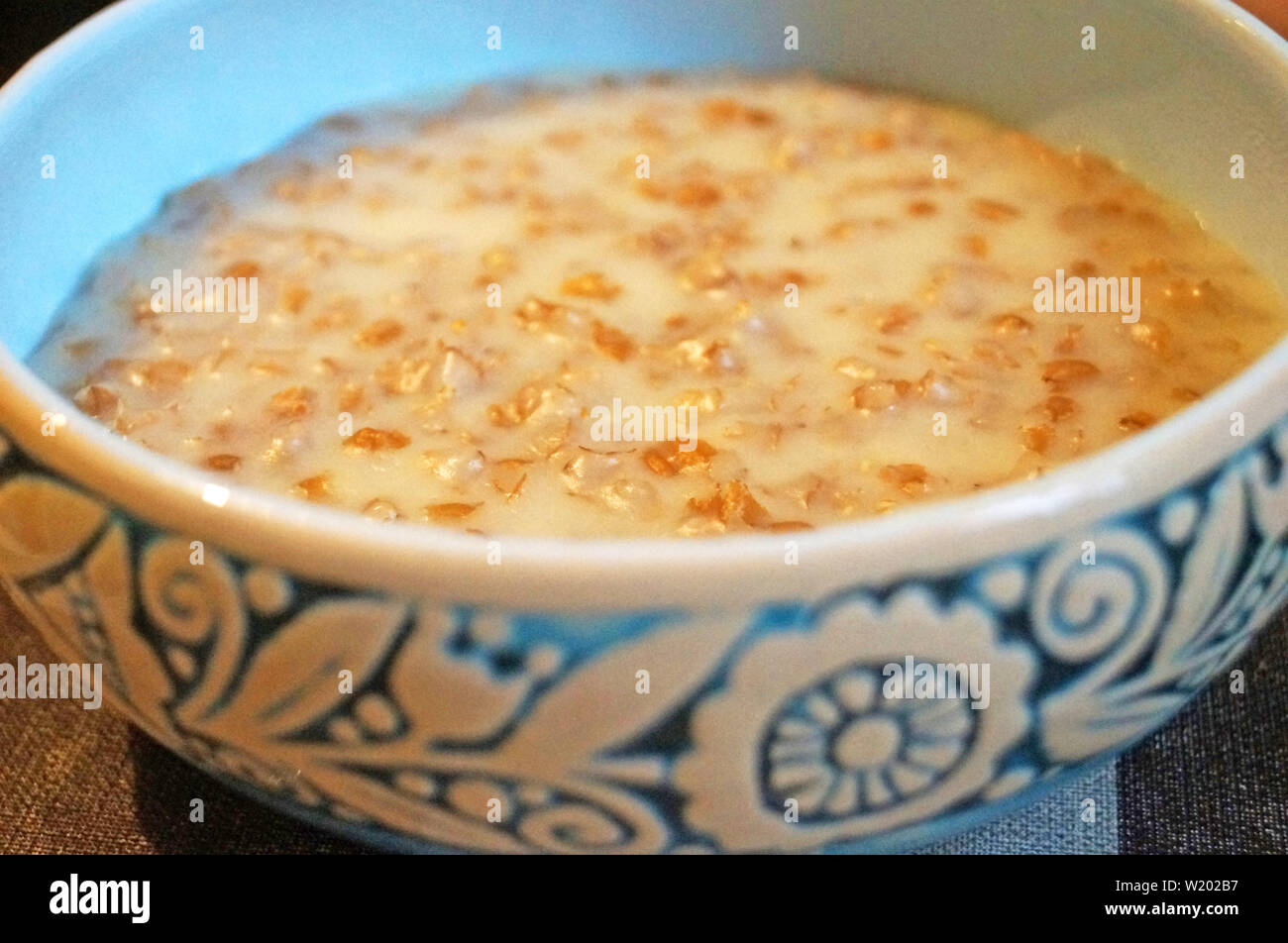 Boiled oatmeal poured into a decorative blue plate on festive salt in ...