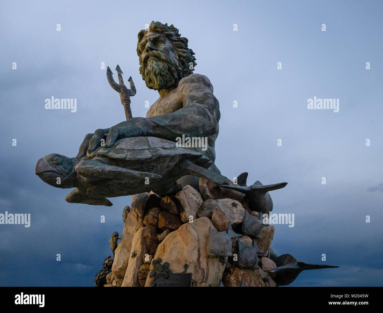 A storm brews behind the statue of king neptune along the beach and ...