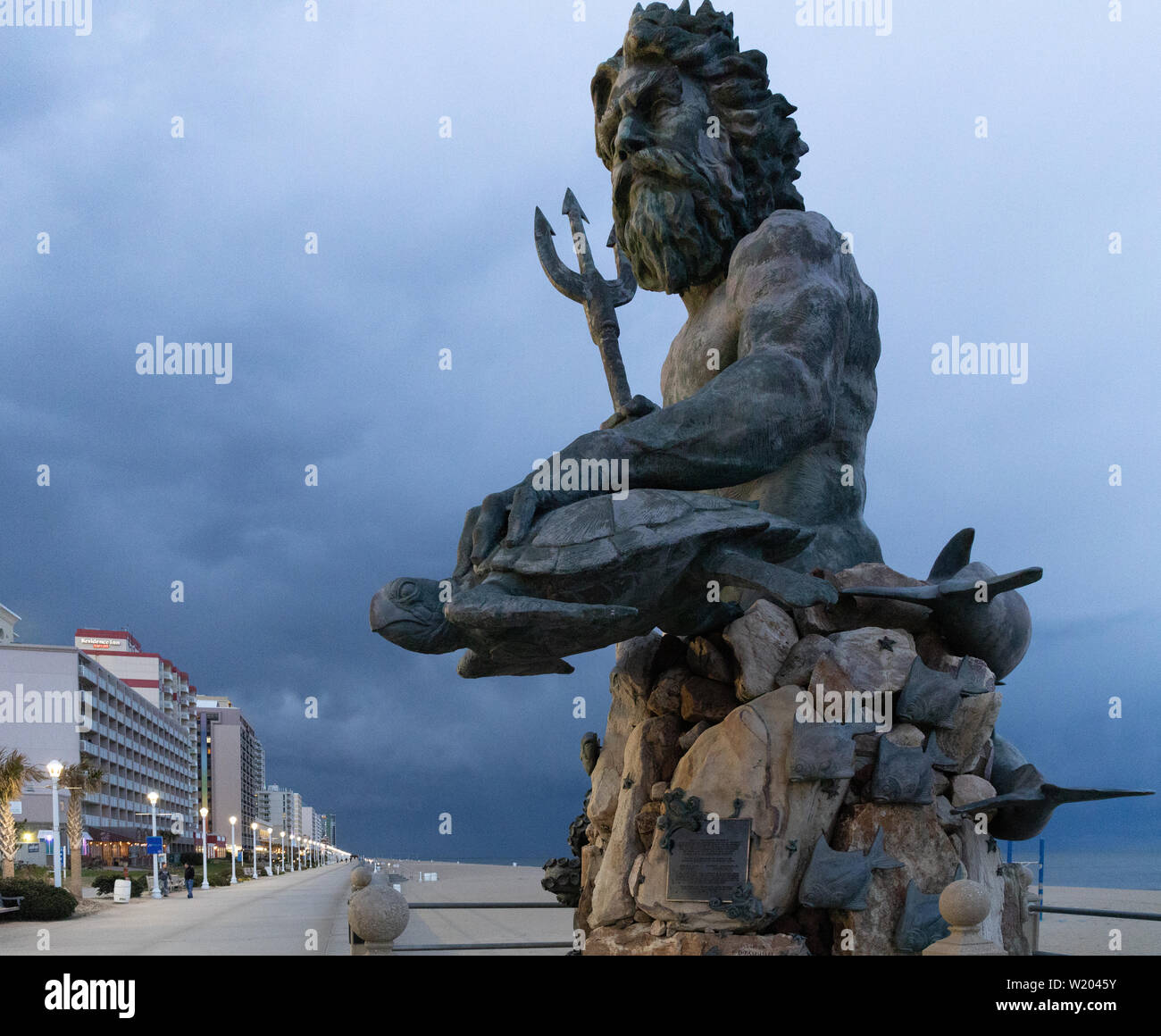 A storm brews behind the statue of king neptune along the beach and ...
