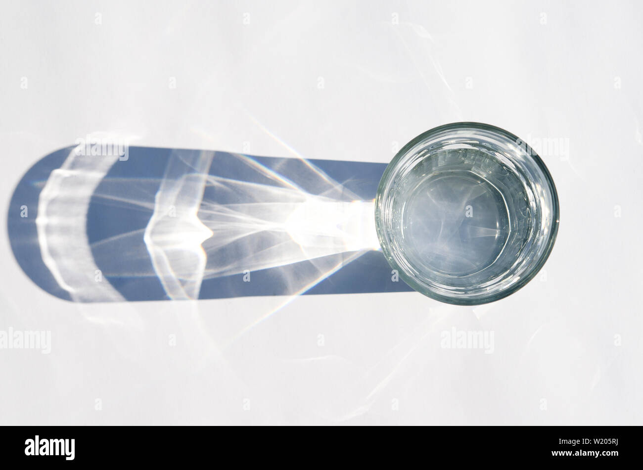 Glass beaker from which padajet sharp shadow, stands on a white ...