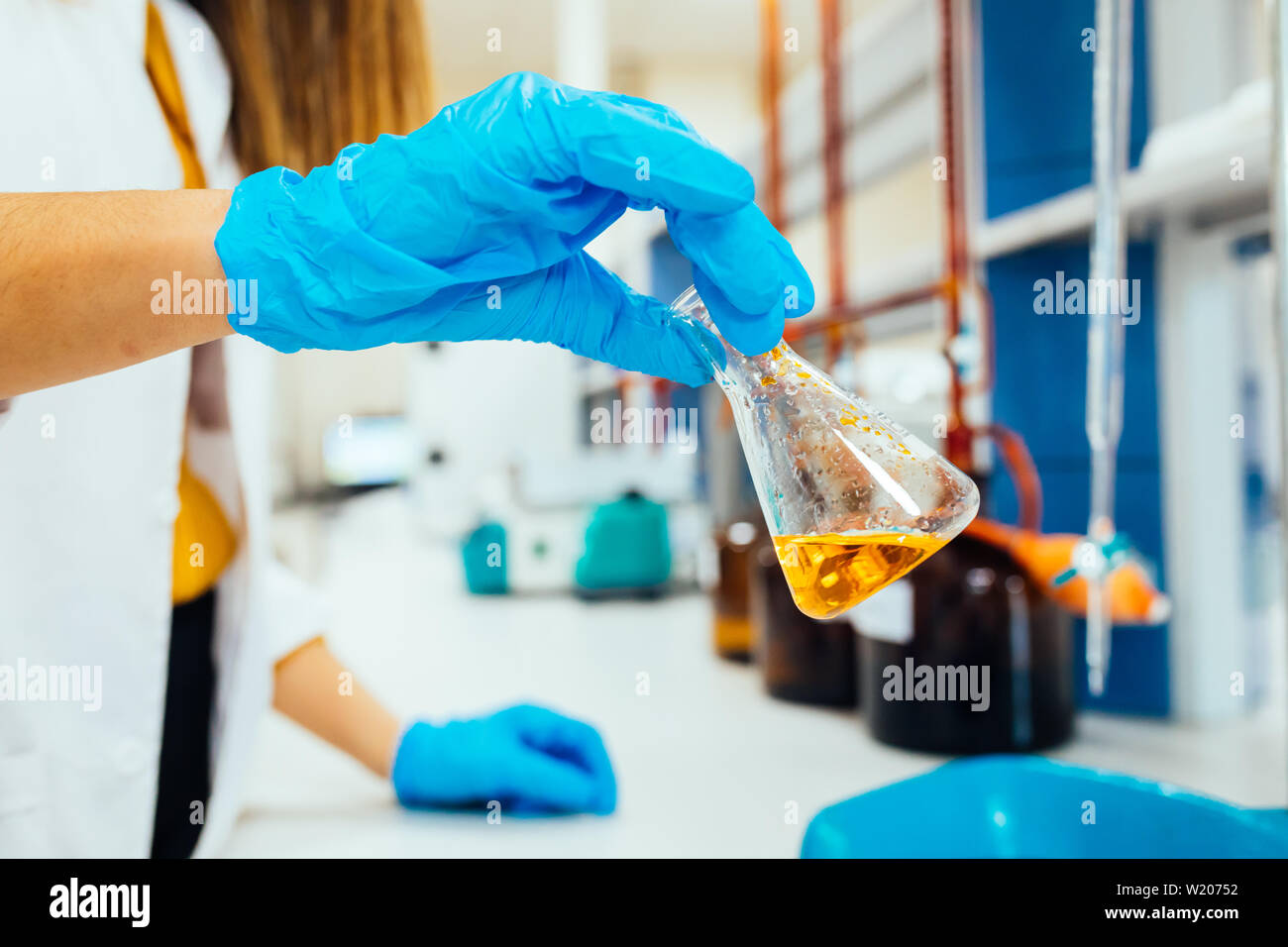 Woman or female hands in protective gloves hold test tube in hands ...
