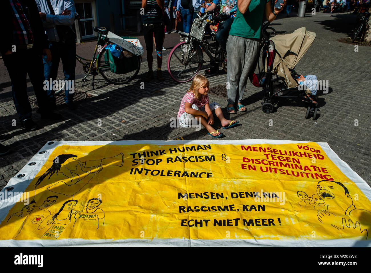 A little girl seats on the ground next to a banner during the protest ...