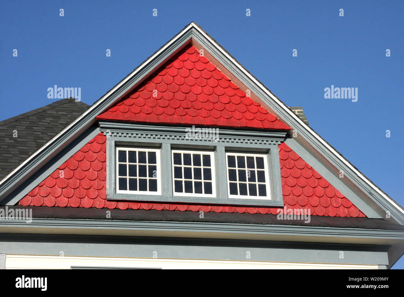 Attic windows surrounded by red shingles on the exterior of a house in ...