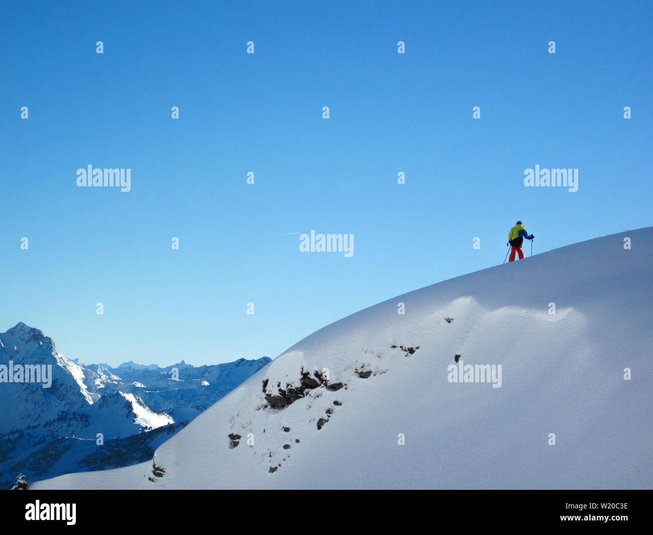 Cliff under snow in front of a mountain panorama in winter in the ...