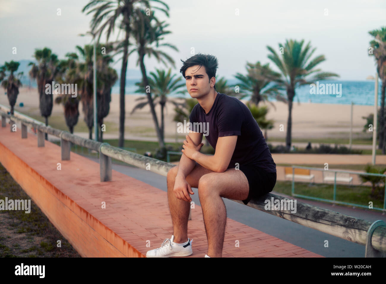 Young athletic man after running at park with skyscrapers background ...