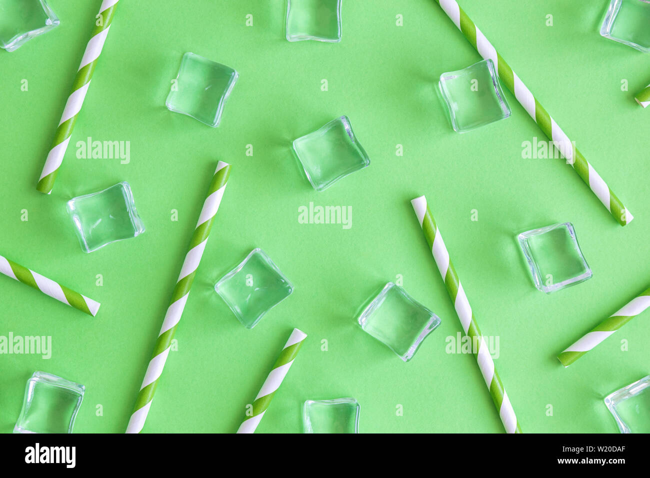 Flat lay of drinking straws and ice cubes on green background minimal ...