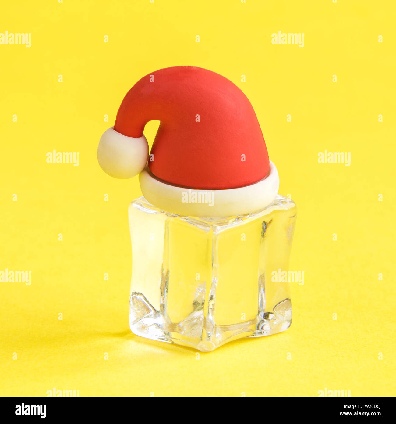 Santa Claus hat on ice cube against yellow background minimal creative ...