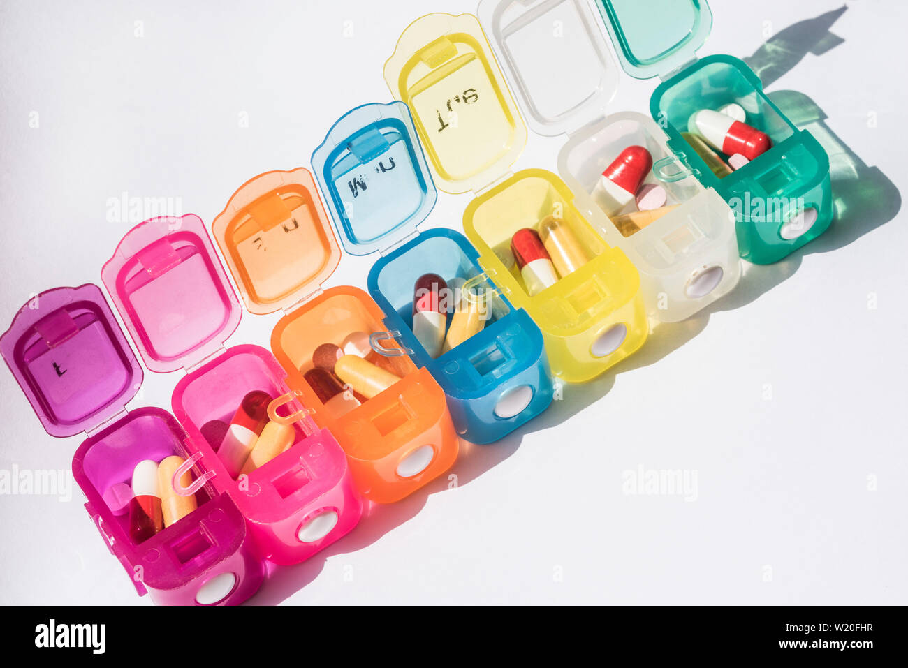 A selection of pills and capsules sat inside small compartments of a ...