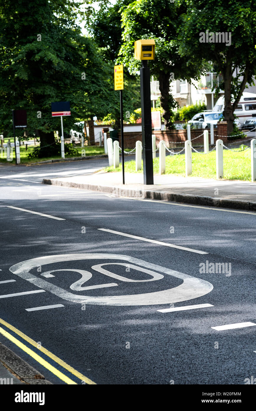 A painted 20mph speed limit in the road with a bright yellow speed ...