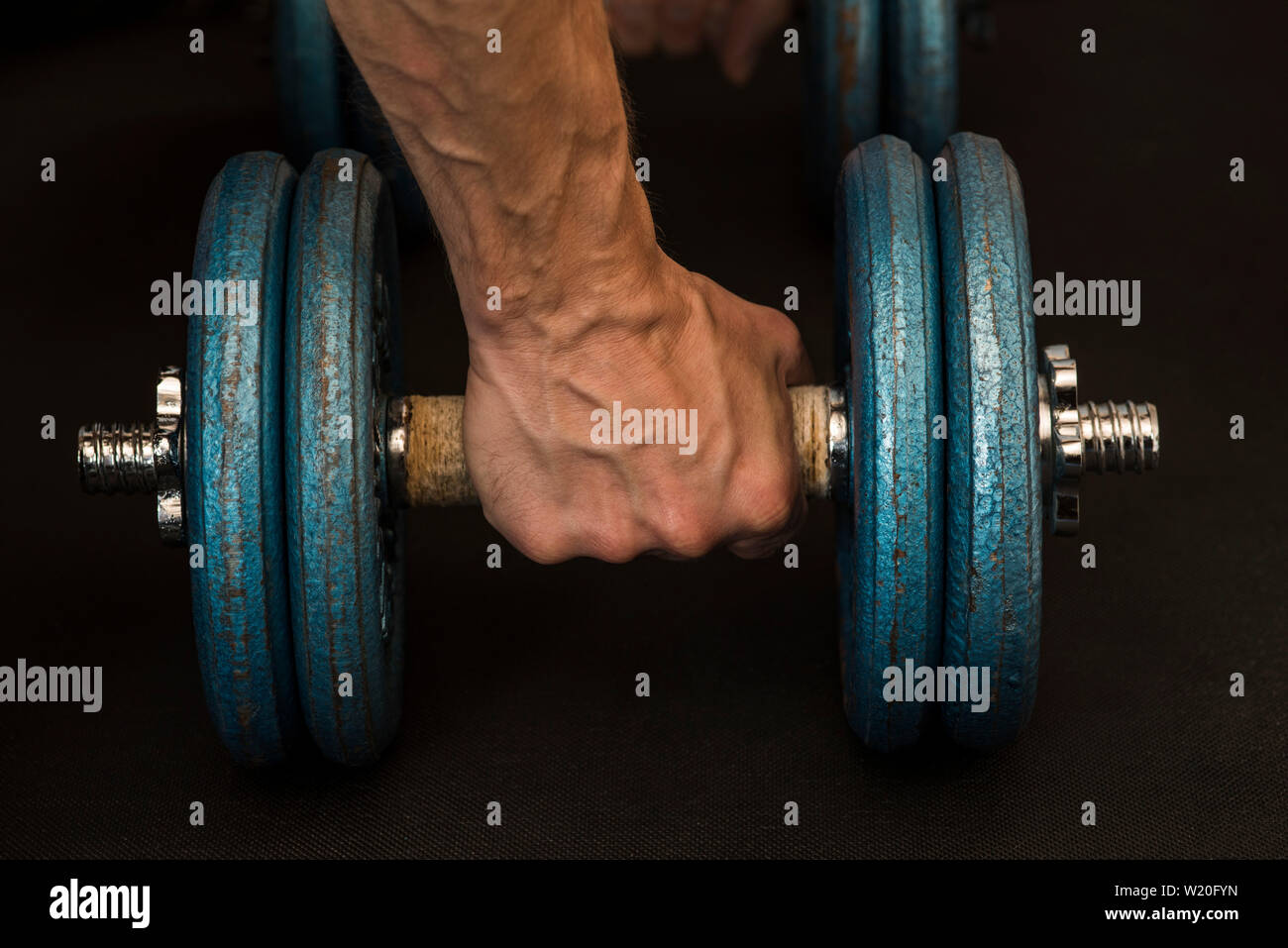 A hand tightly gripping a 22kg dumbbell revealing bulbous veins in the ...