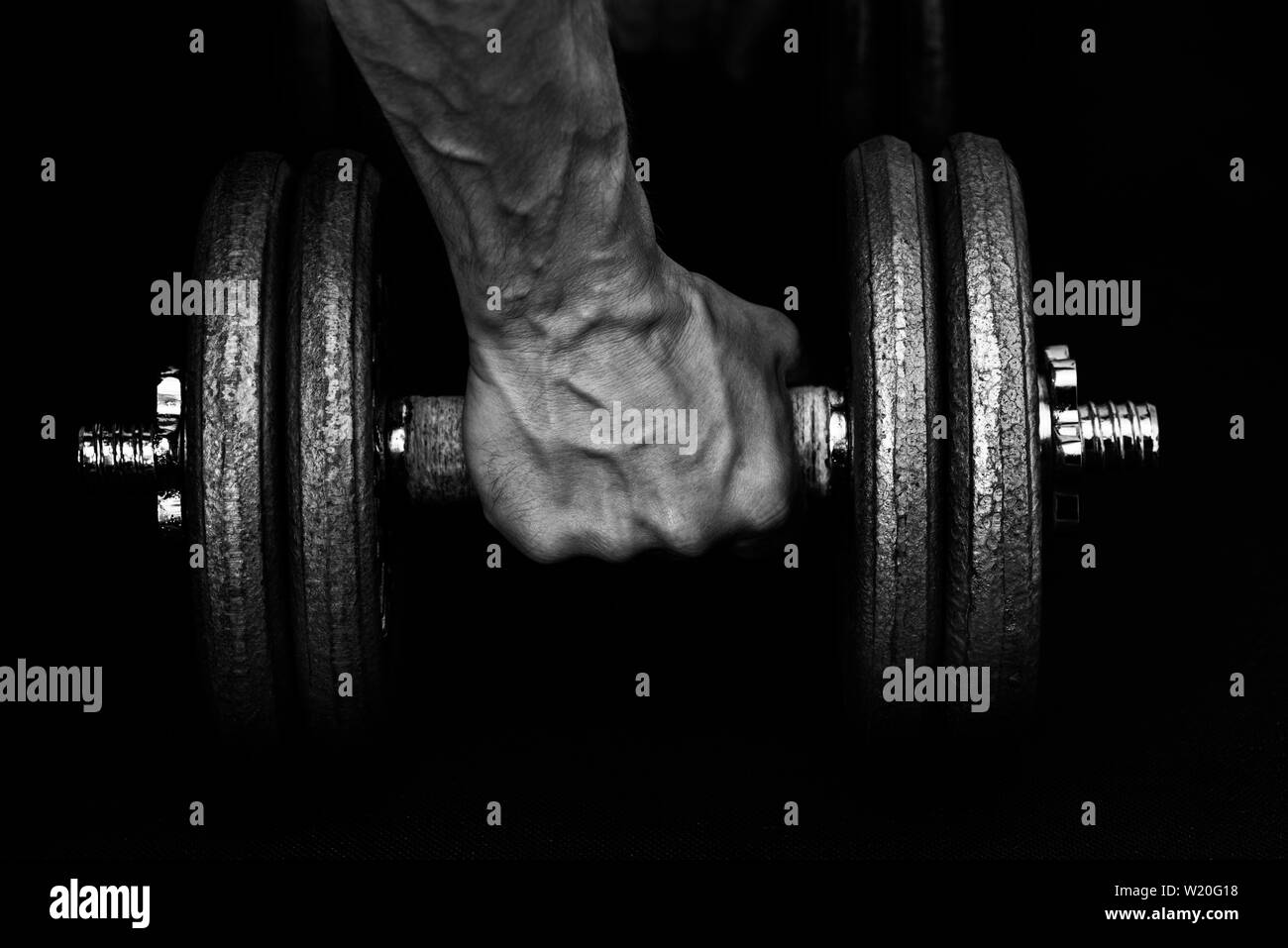 A hand tightly gripping a 22kg dumbbell revealing bulbous veins in the ...
