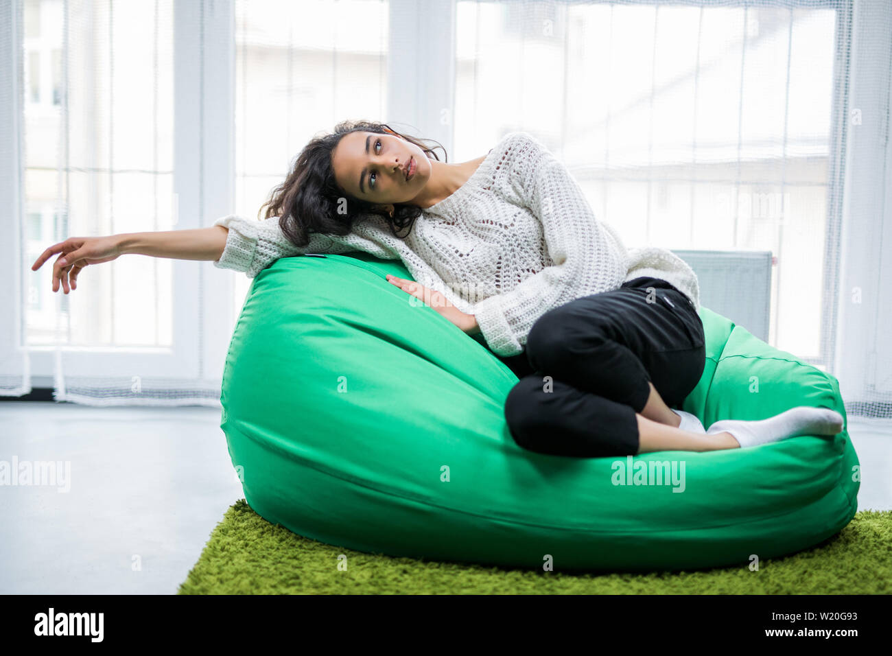 Young woman lying on puff and relaxing at home Stock Photo - Alamy