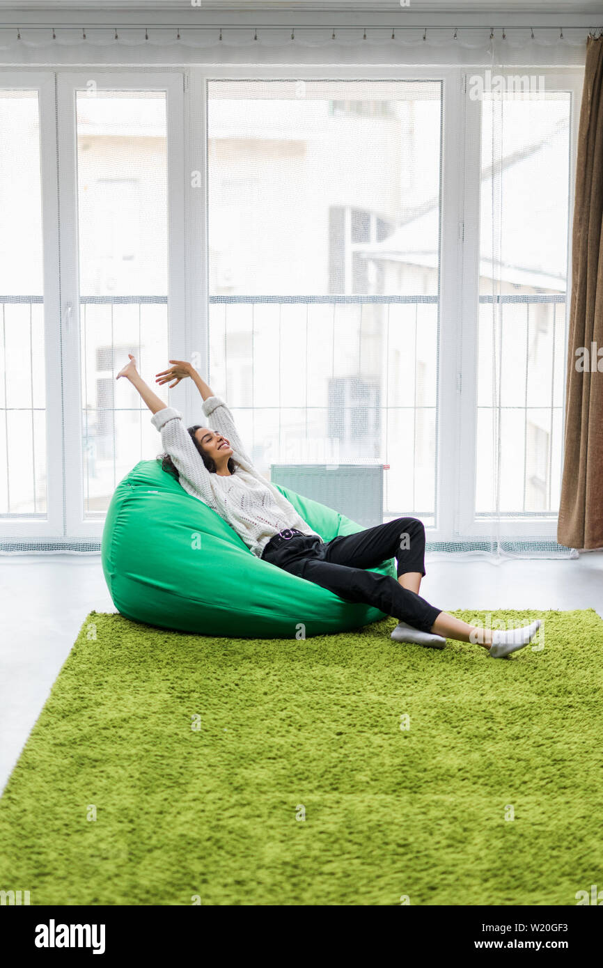 Young woman stretching while lying on the poof at home Stock Photo - Alamy