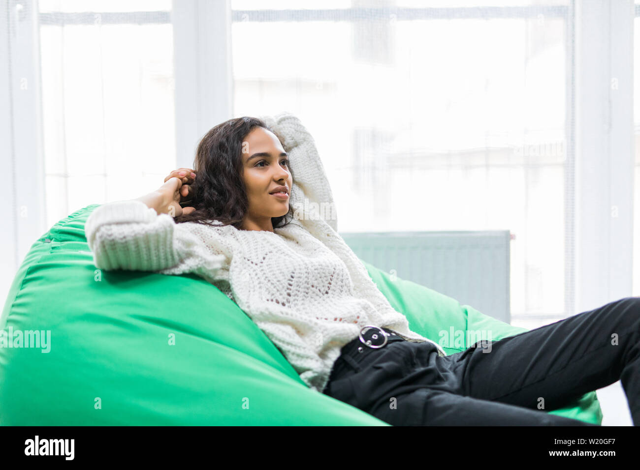 Young woman relaxing on poof at home Stock Photo - Alamy