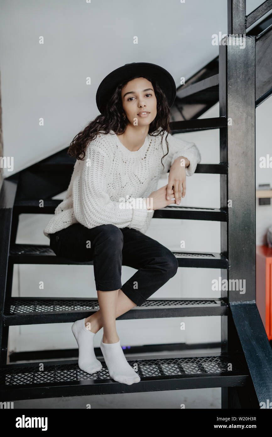 Pretty young smiling woman sitting on steps at home Stock Photo - Alamy