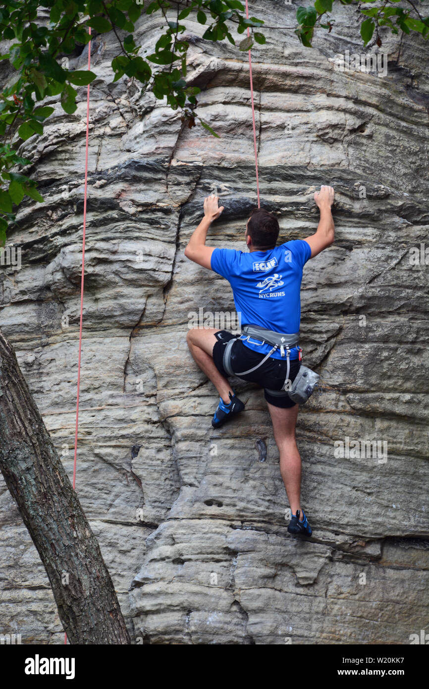 A young male climber works his way up a cliff face on the Ledge Spring ...