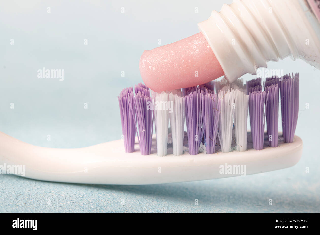 Toothbrush with pink toothpaste next to a tube of toothpaste against ...