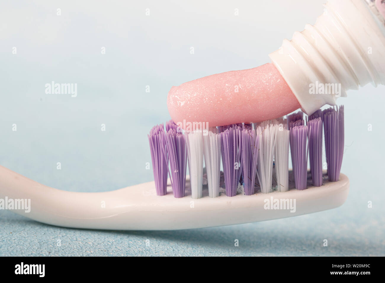 Toothbrush with pink toothpaste next to a tube of toothpaste against ...