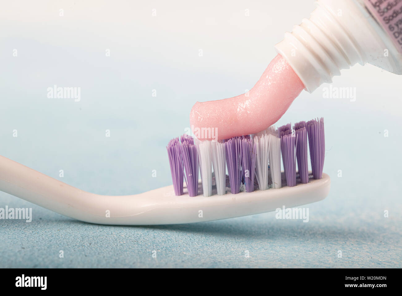 Toothbrush with pink toothpaste next to a tube of toothpaste against ...