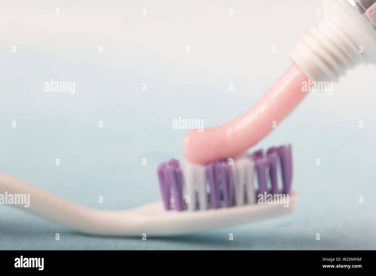 Toothbrush with pink toothpaste next to a tube of toothpaste against ...