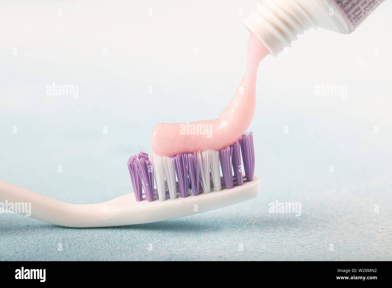 Toothbrush with pink toothpaste next to a tube of toothpaste against ...