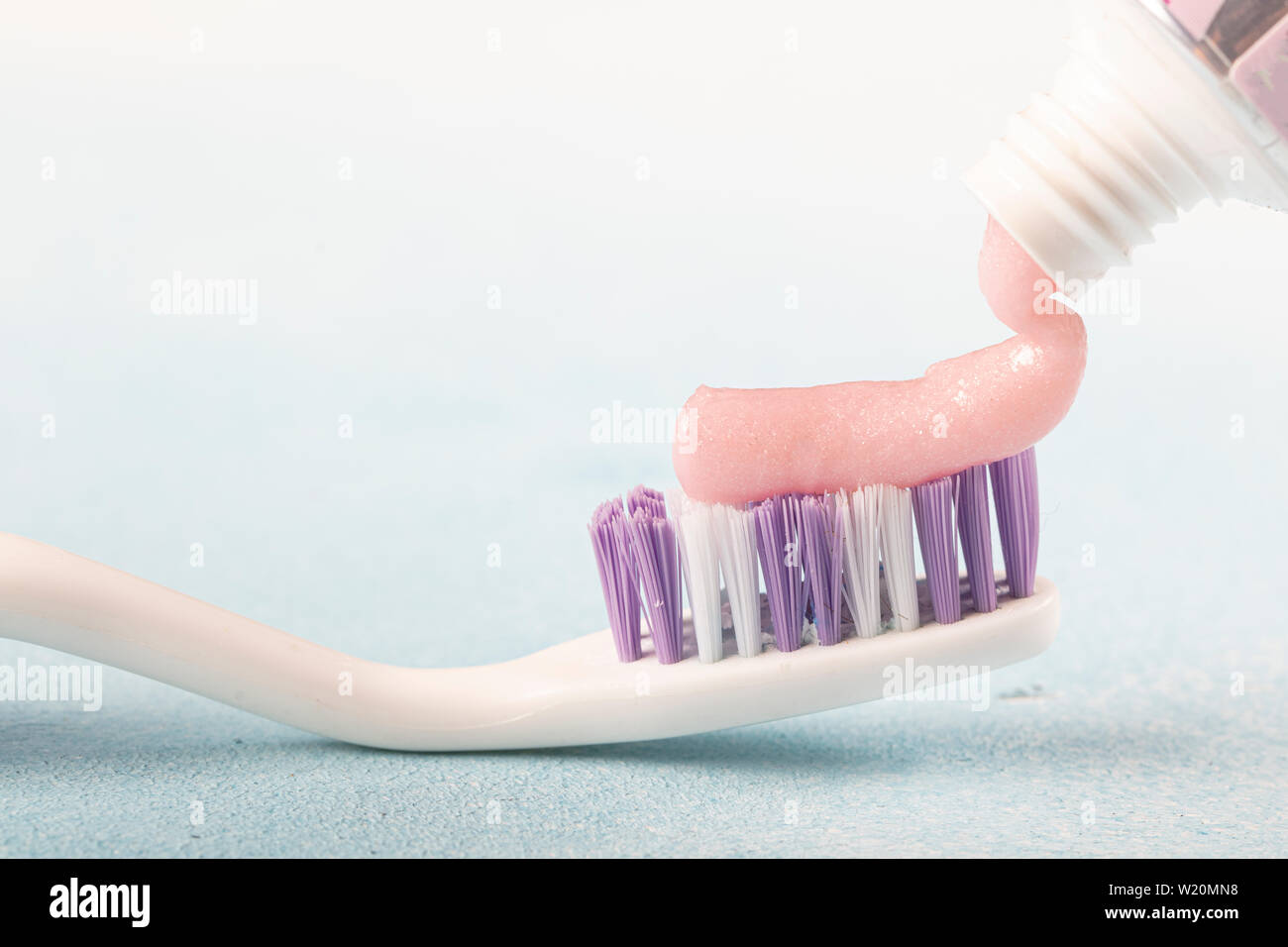 Toothbrush with pink toothpaste next to a tube of toothpaste against ...