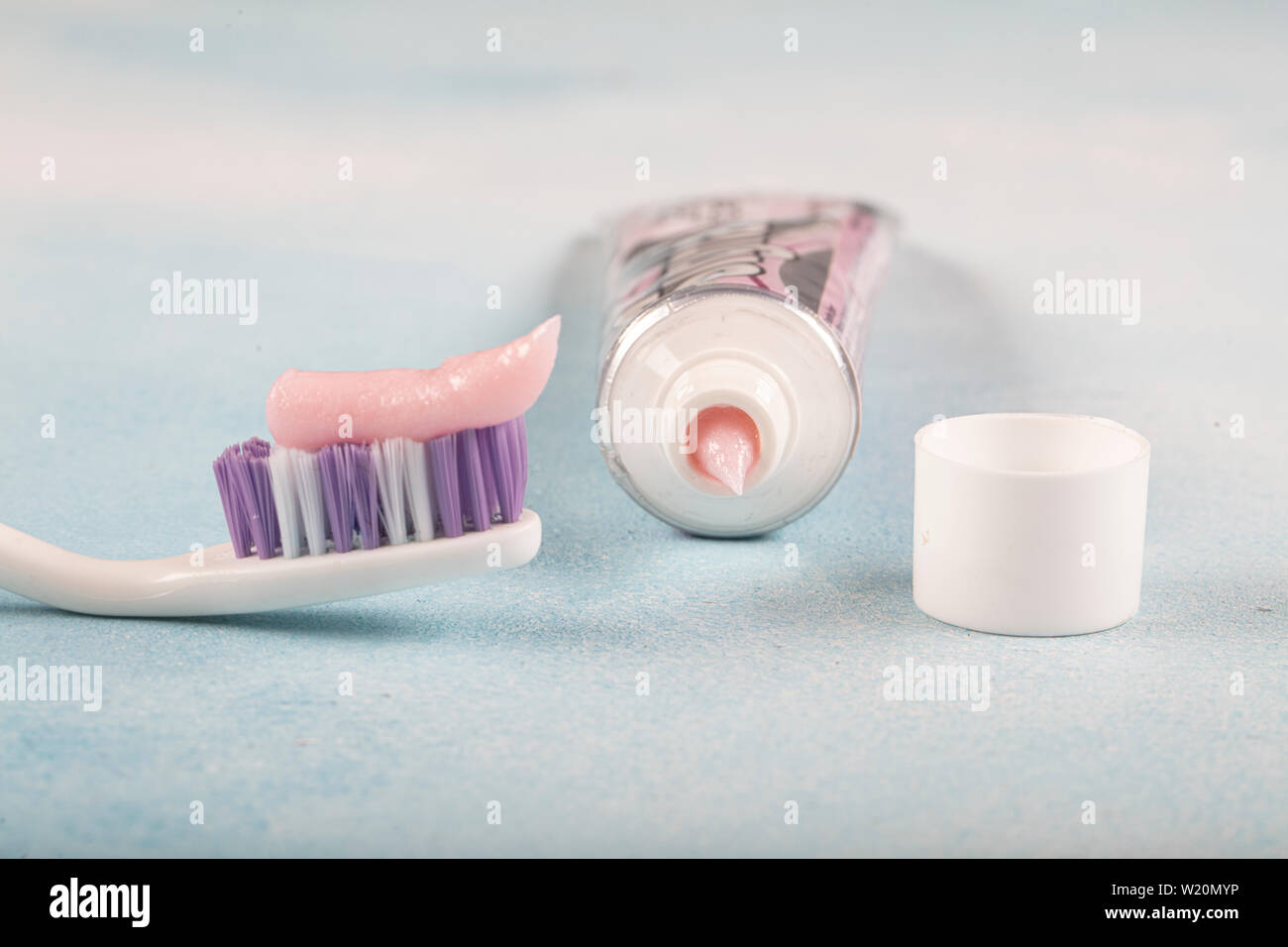 Toothbrush with pink toothpaste next to a tube of toothpaste against ...