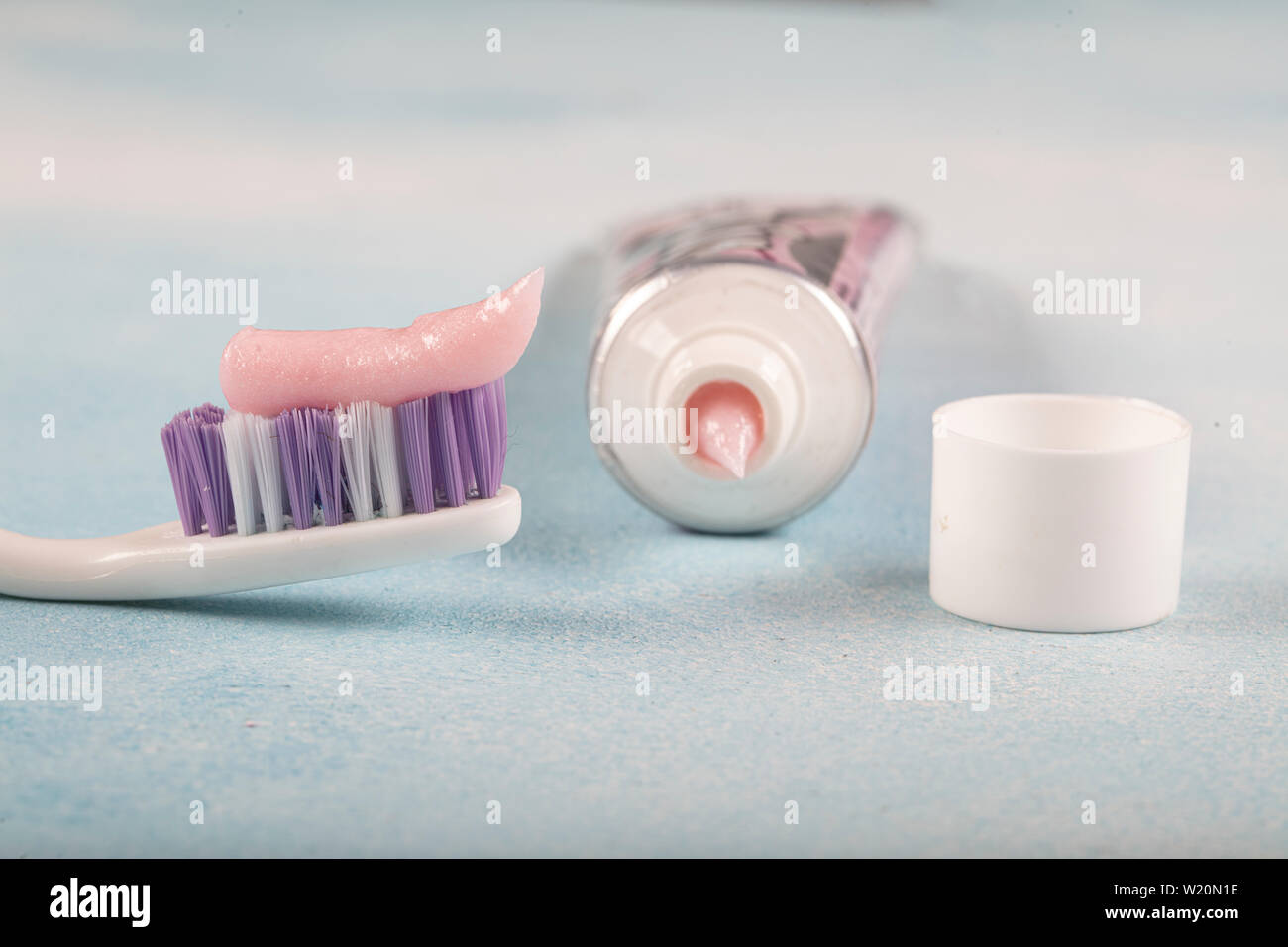 Toothbrush with pink toothpaste next to a tube of toothpaste against ...