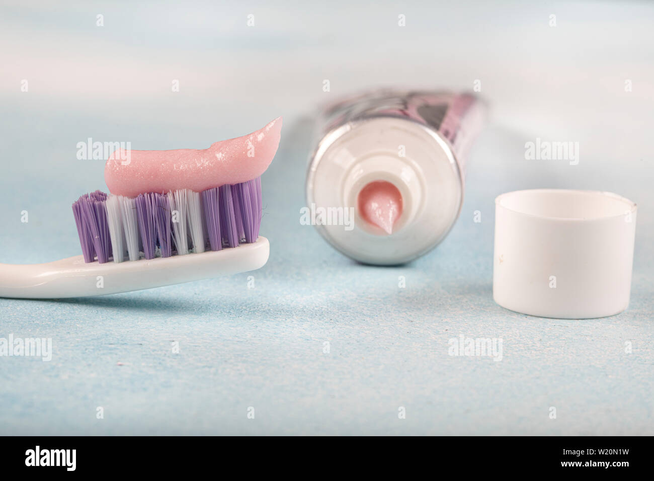 Toothbrush with pink toothpaste next to a tube of toothpaste against ...