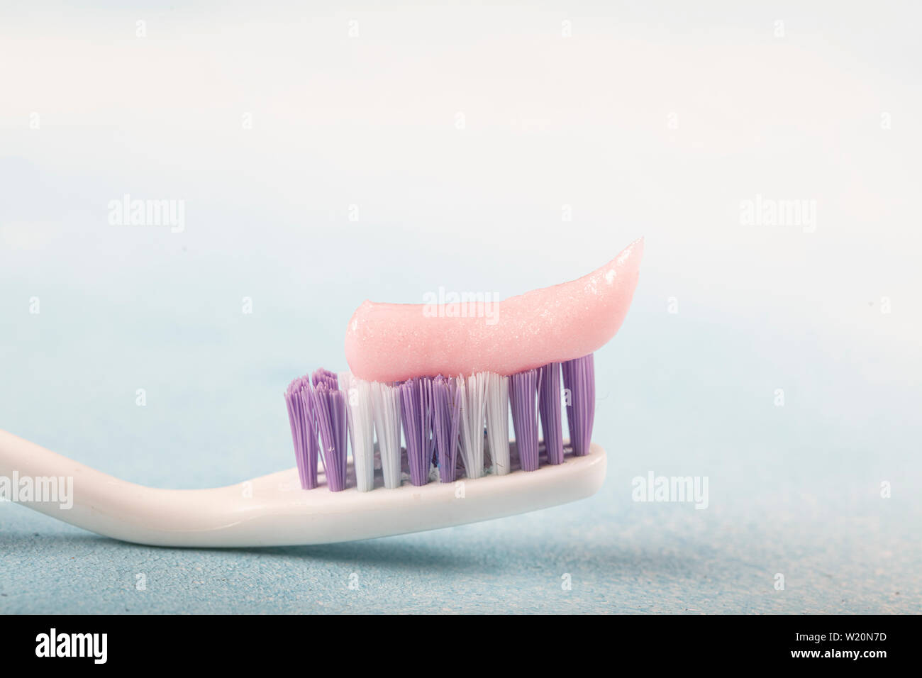 Toothbrush with pink toothpaste next to a tube of toothpaste against ...
